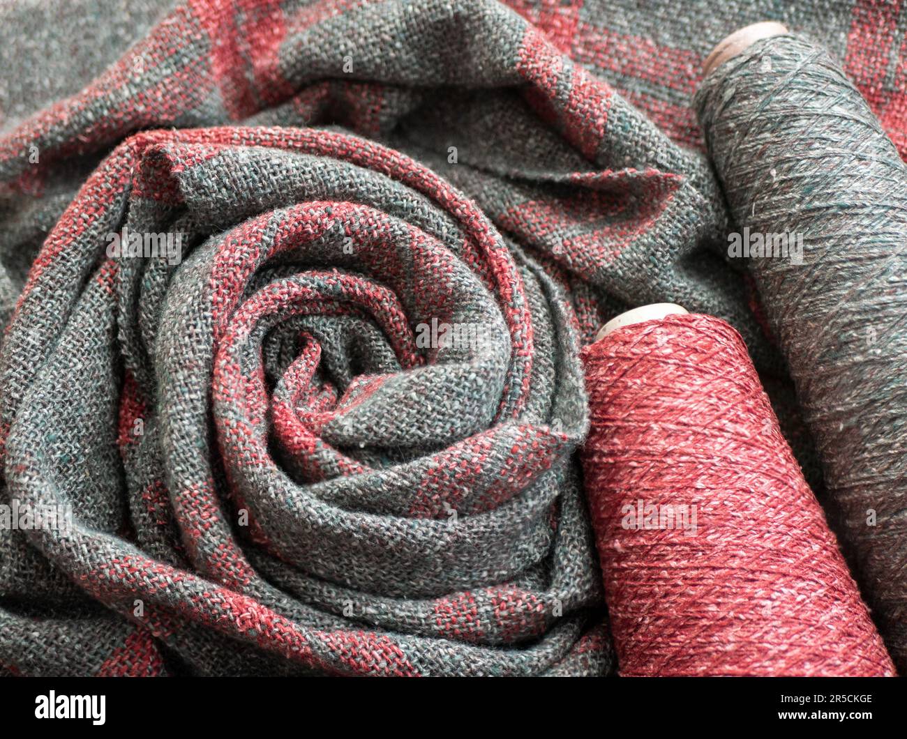 Woven red and gray tweed scarf or shawl and two bobbins with threads ...