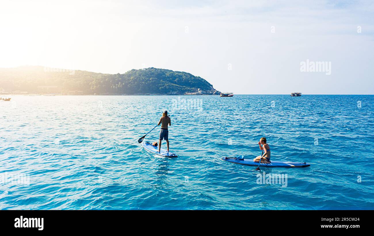 Summer is for stand up paddle boarding. a man and woman paddle boarding ...