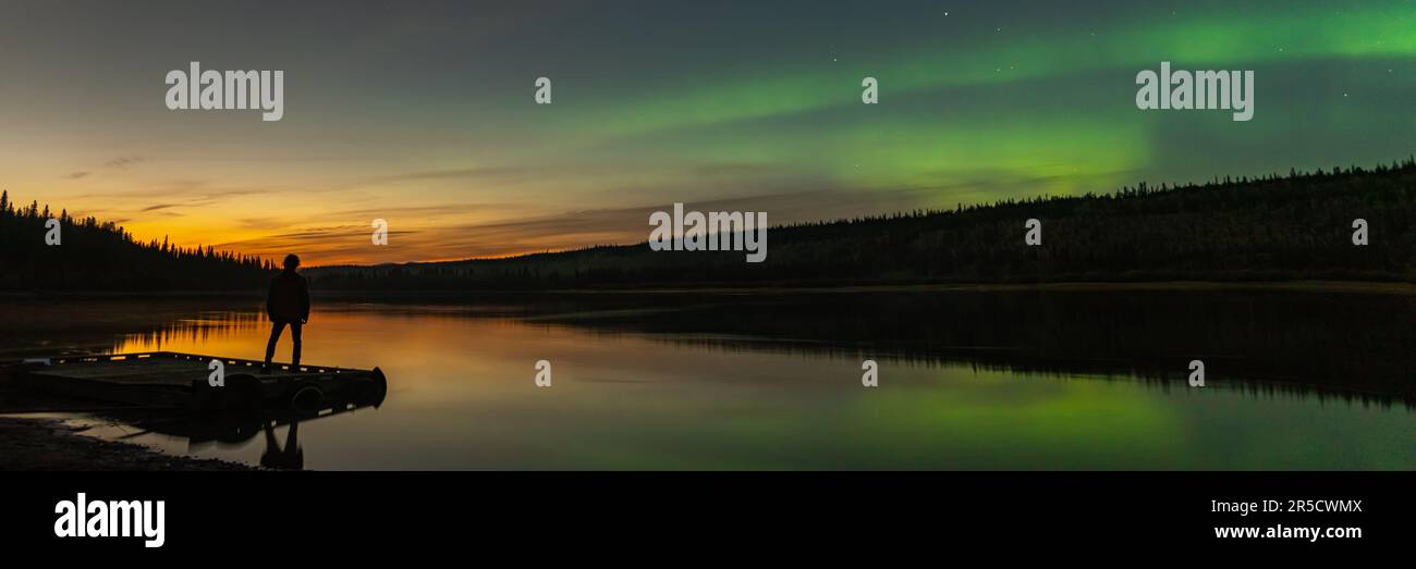 One person, standing along side open river at sunset with beautiful ...