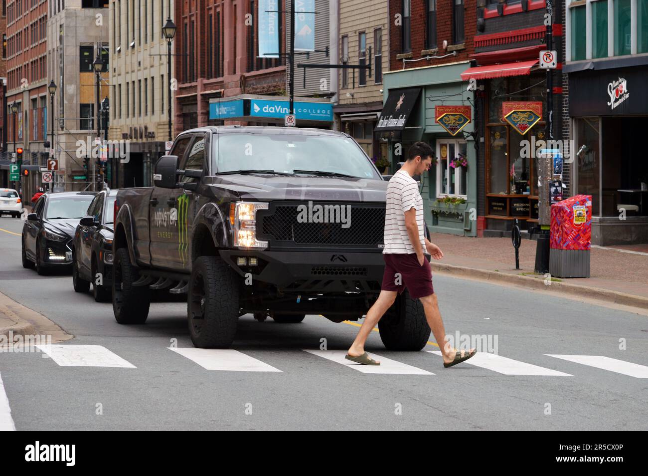 Man crossing the street in front of a lifted pickup truck in downtown ...