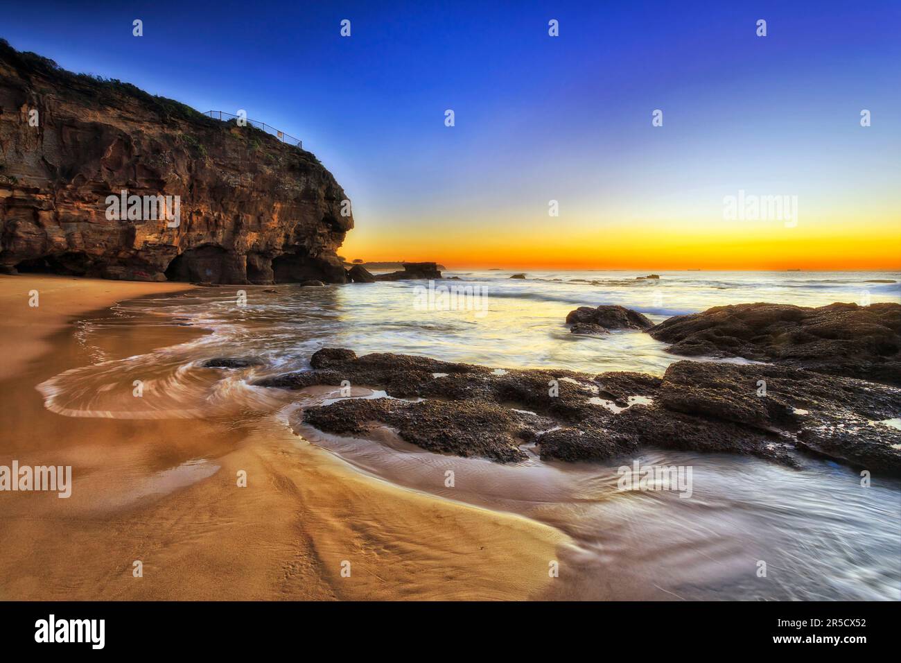 Low tide waves on sands and rocks of Caves beach around sea caves of ...