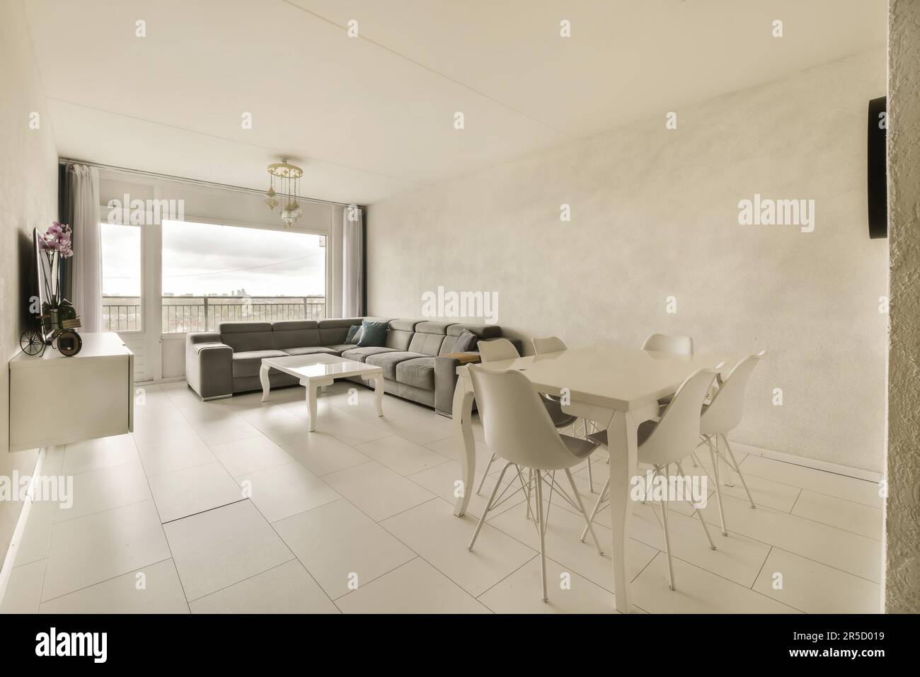 a living room with white tile flooring and an open - plan dining area ...