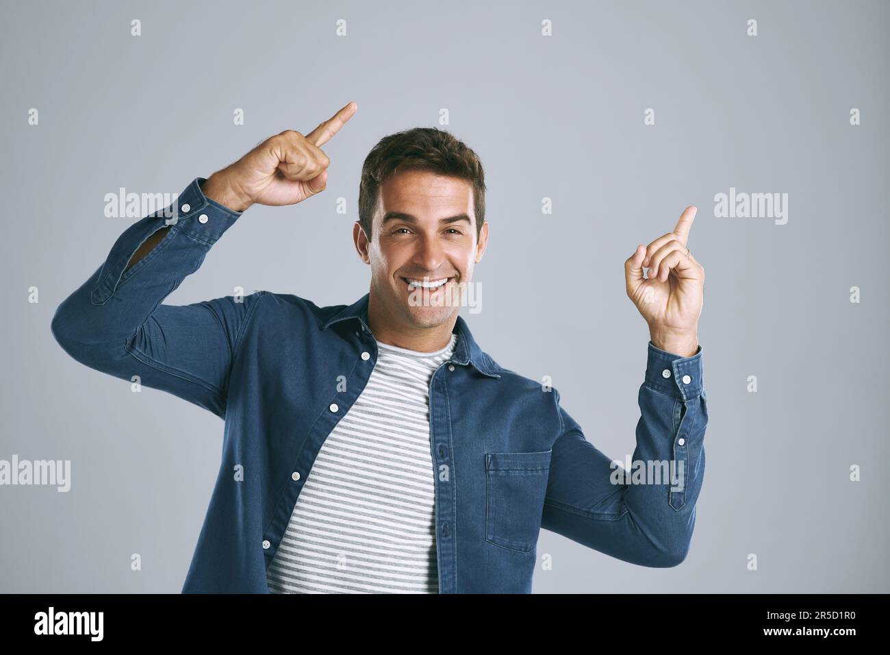 Youre in luck. a man pointing up against a grey background Stock Photo ...