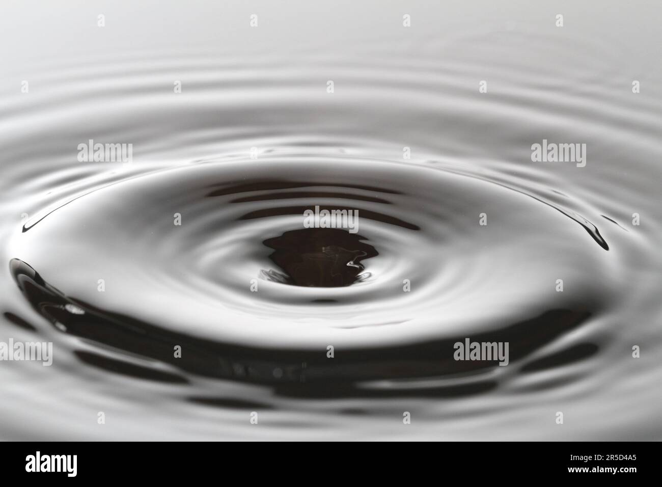 Beautiful water drops splashing on still water Stock Photo - Alamy