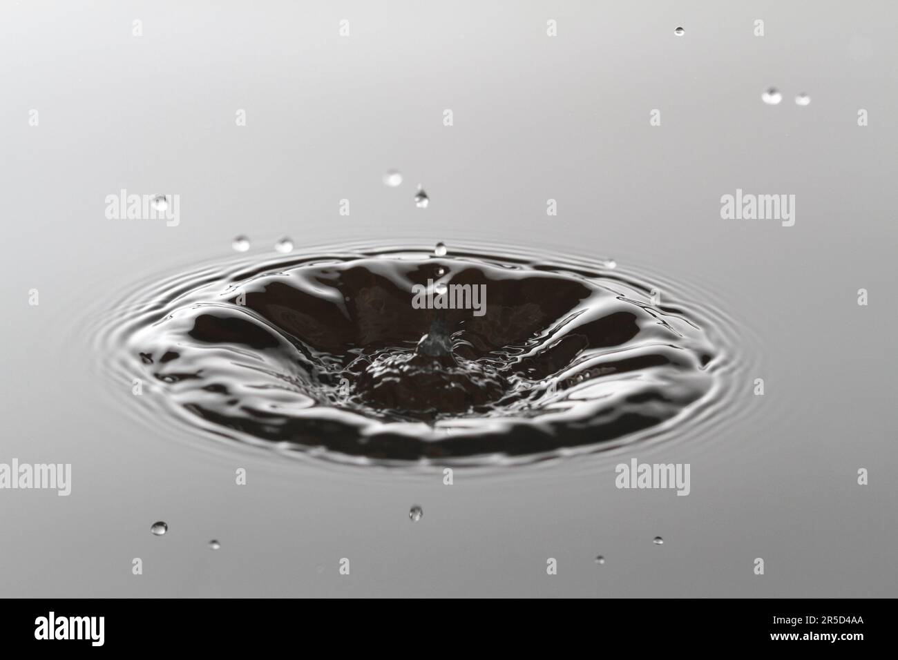 Beautiful water drops splashing on still water Stock Photo - Alamy