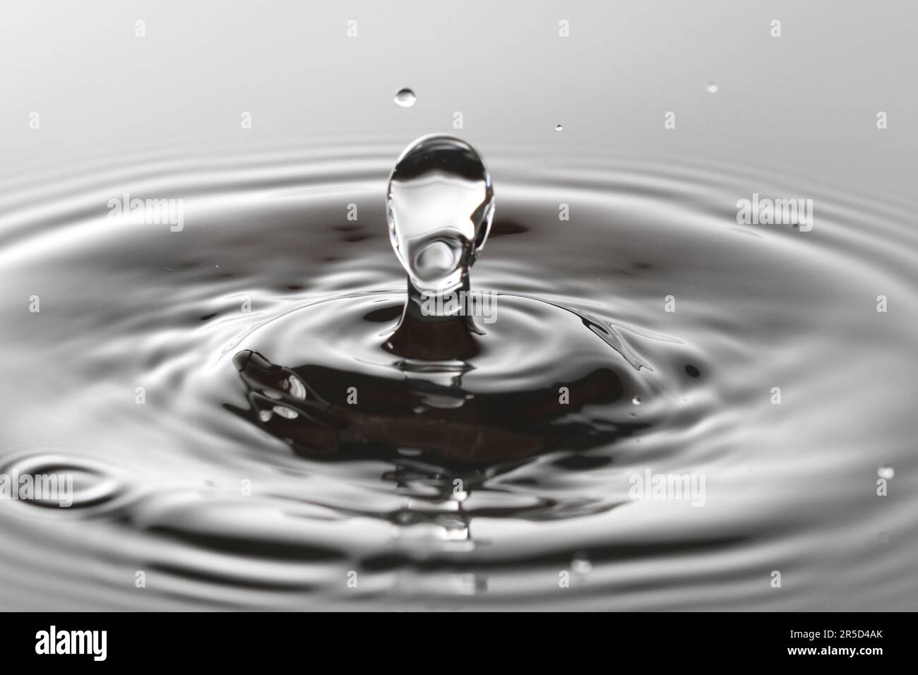 Beautiful water drops splashing on still water Stock Photo - Alamy