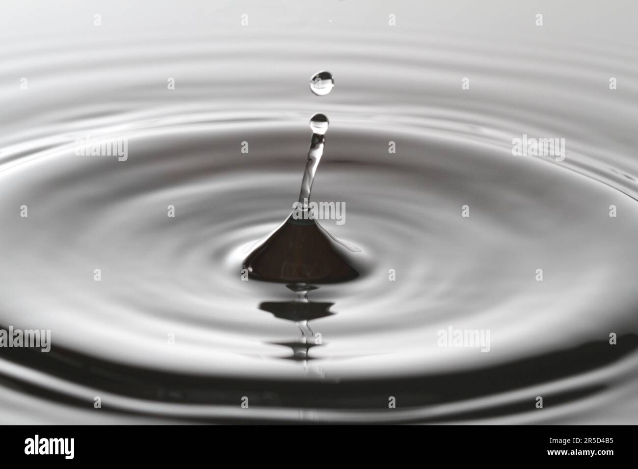 Beautiful water drops splashing on still water Stock Photo - Alamy