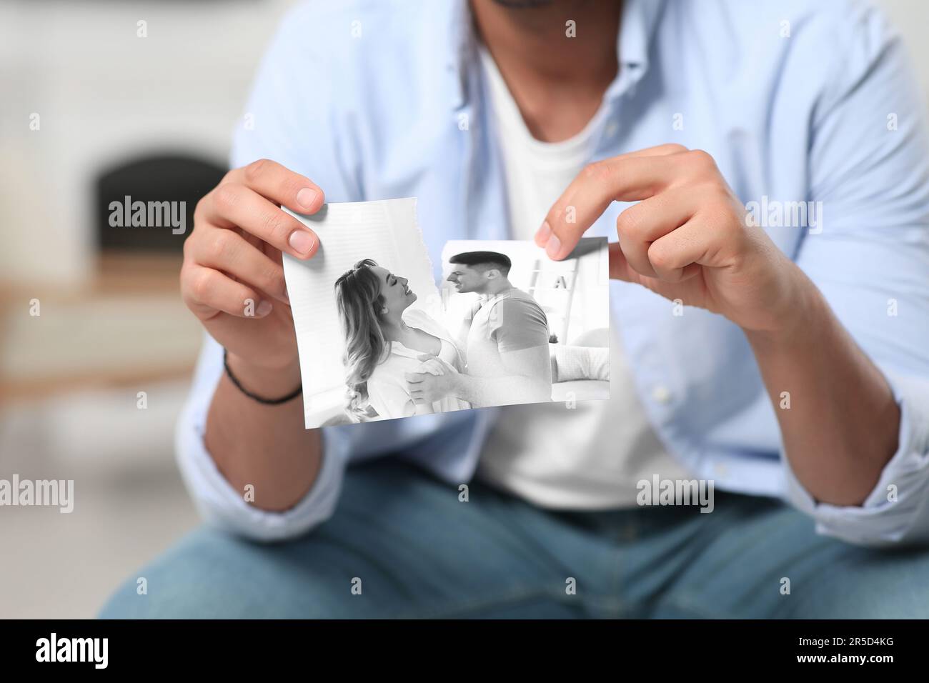 Divorce and breakup. Man ripping photo at home, closeup. Black and ...