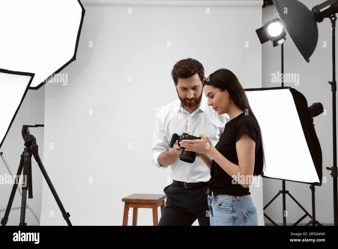 Professional photographer and model looking at pictures on camera in ...