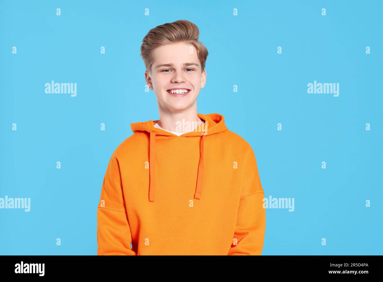 Portrait of smiling teenage boy on light blue background Stock Photo ...