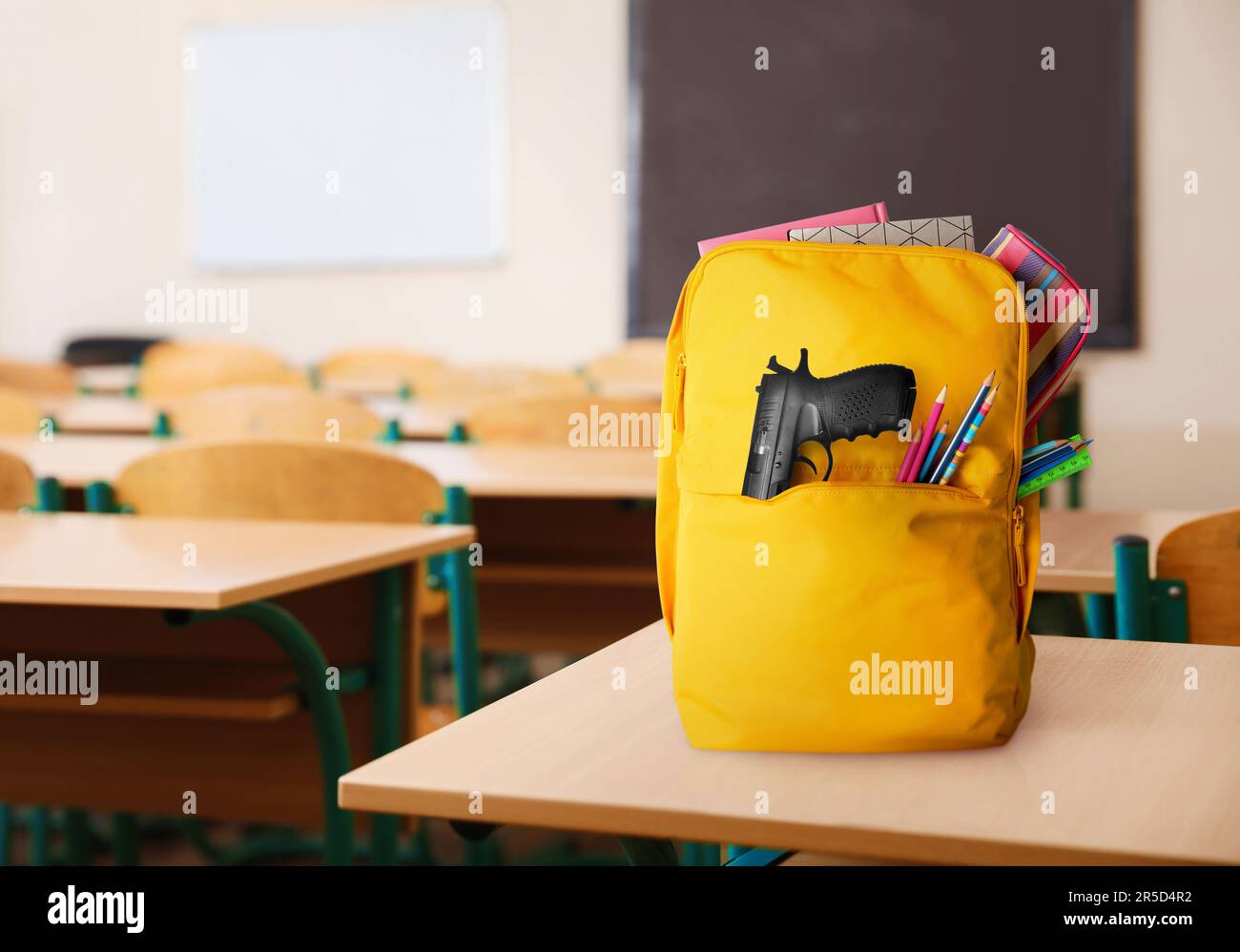 School shooting. Backpack with gun and stationery in classroom Stock ...