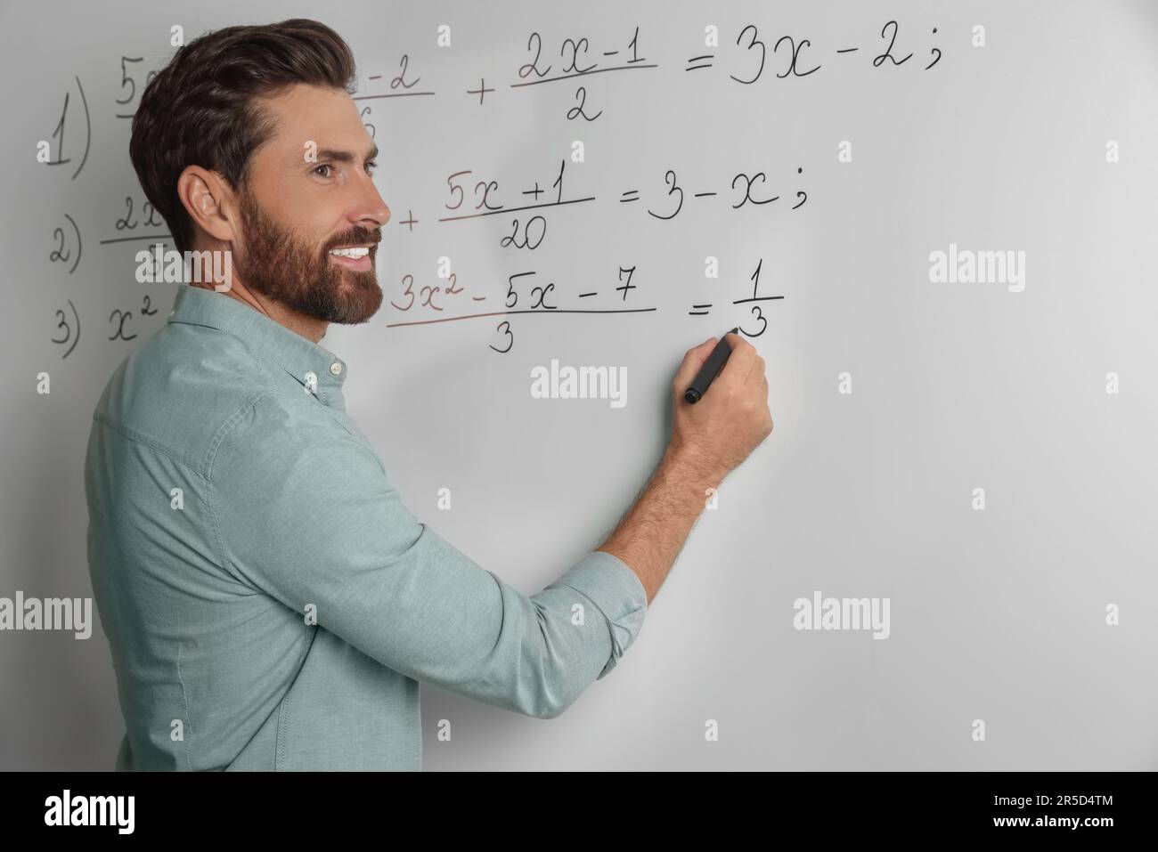 Happy teacher explaining mathematics at whiteboard in classroom Stock ...