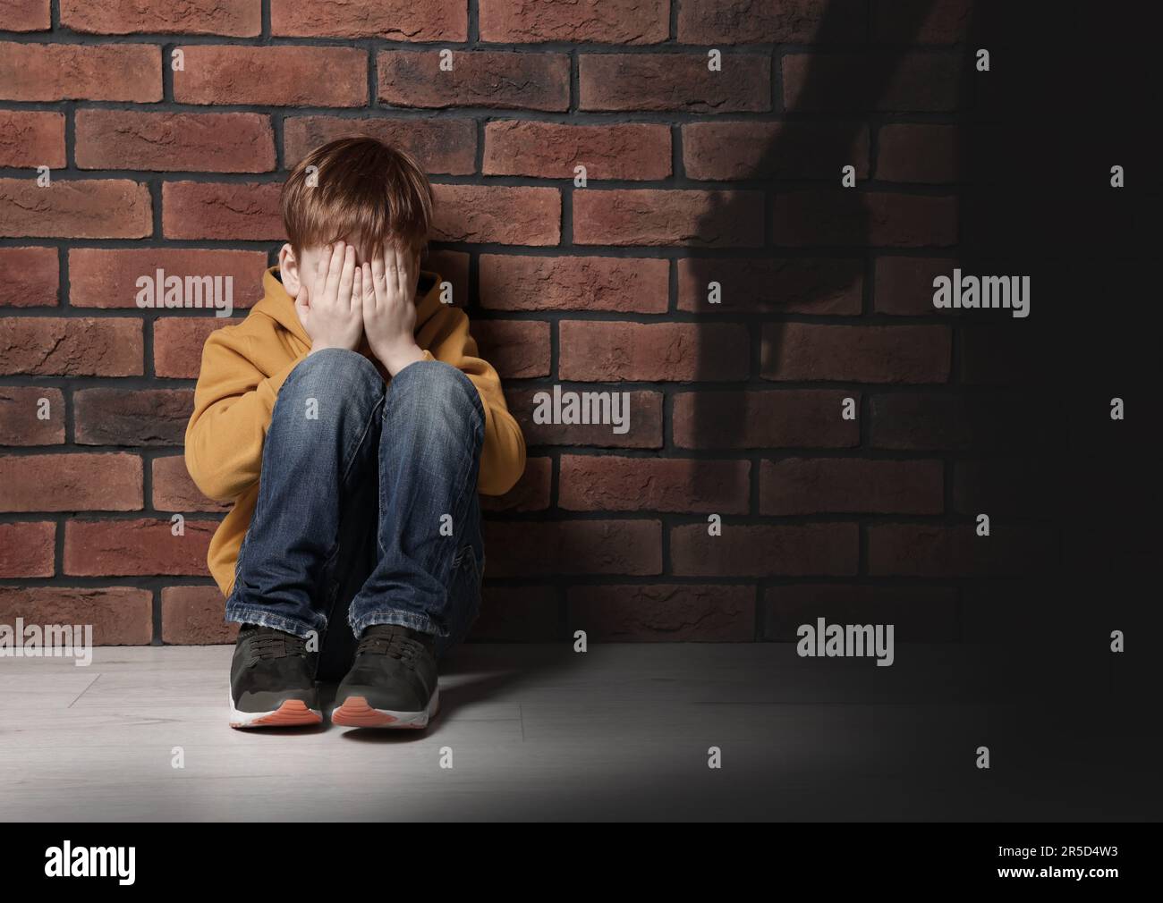 School shooting. Scared little boy and shadow of man with gun indoors ...