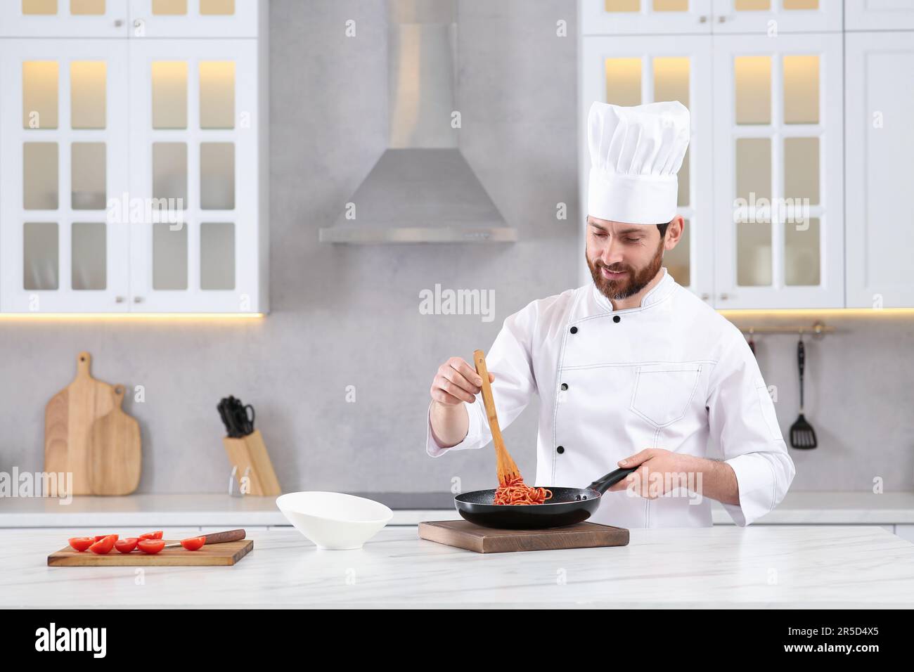 Professional chef with delicious spaghetti at marble table in kitchen ...