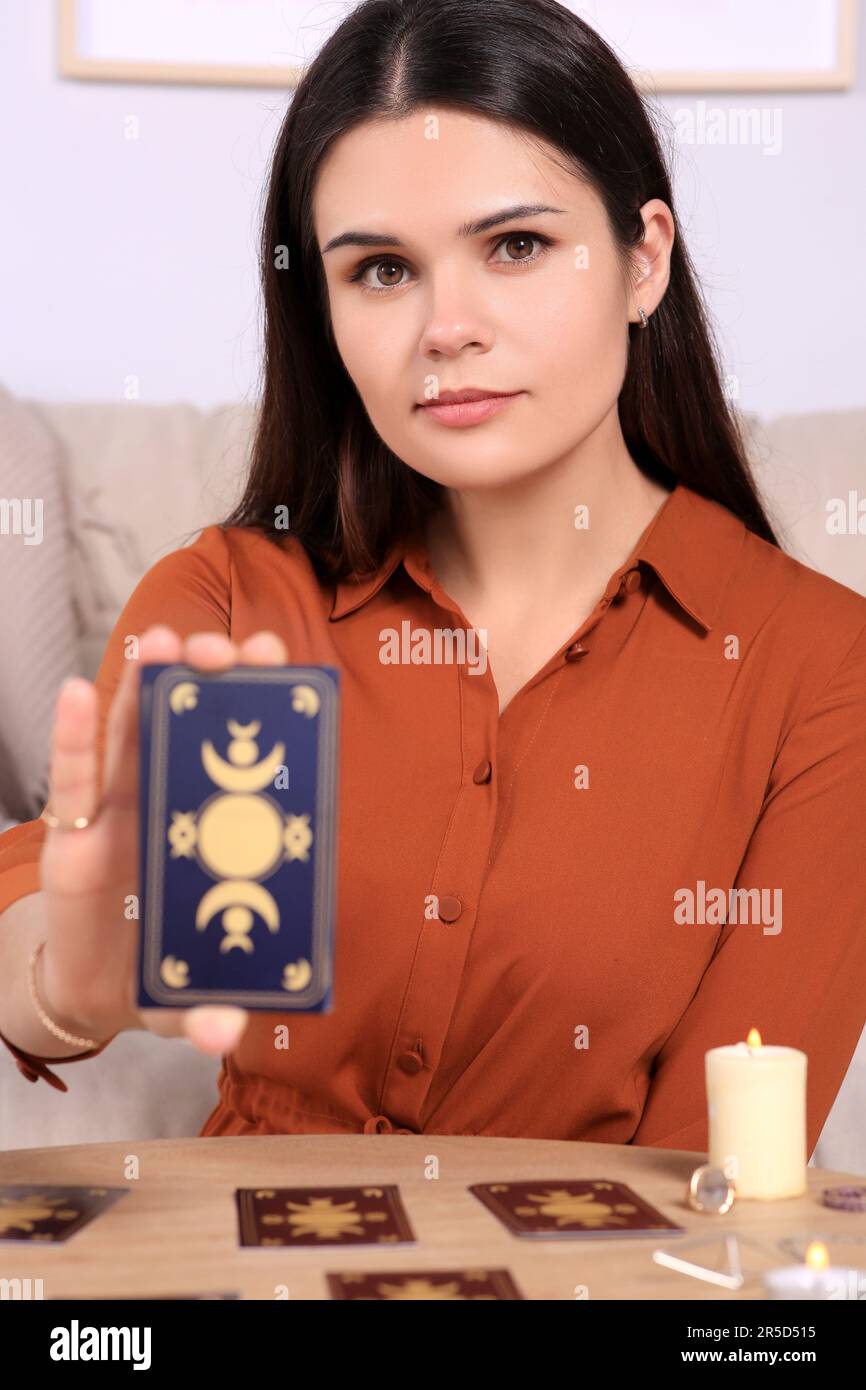Soothsayer showing tarot cards at table indoors. Fortune telling Stock ...