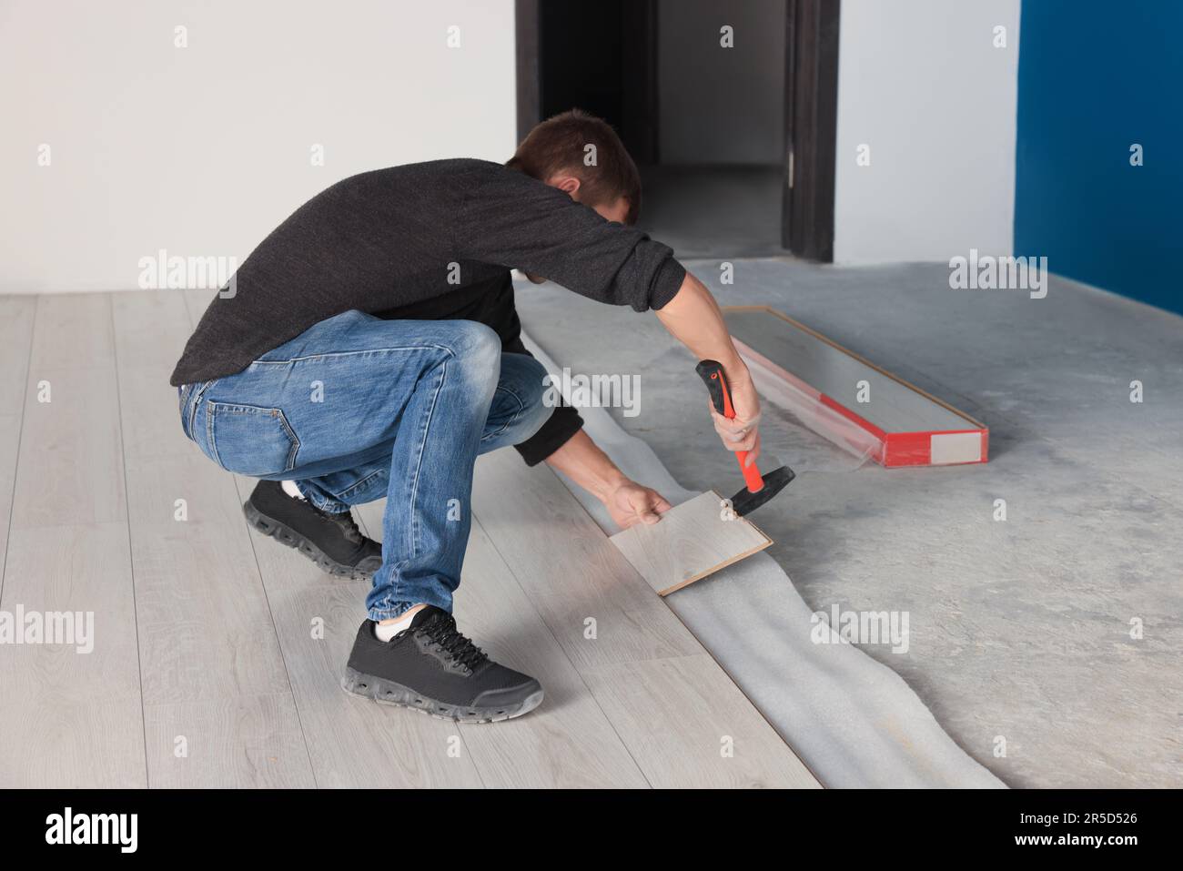 Professional worker using hammer during installation of new laminate ...
