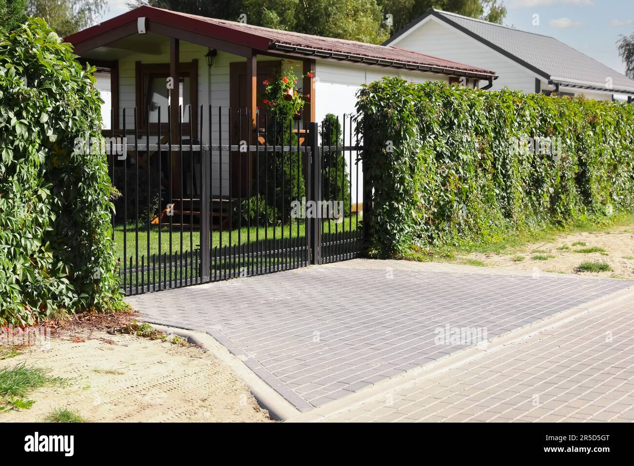 Closed metal gates near houses and green hedge Stock Photo - Alamy
