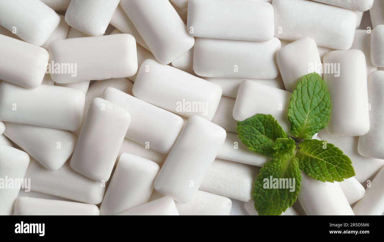 Tasty chewing gums and fresh mint leaves as background, top view Stock ...