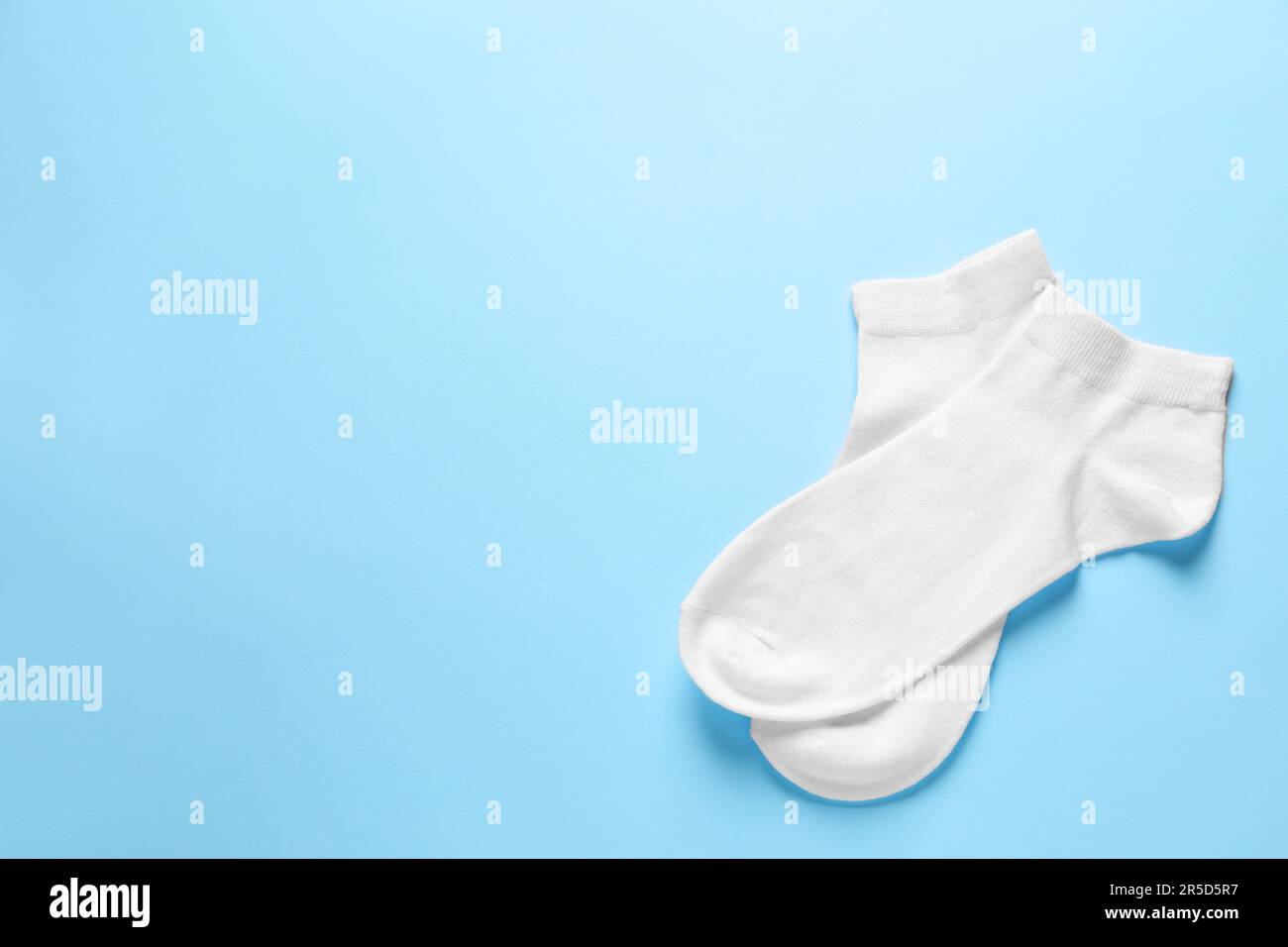 Pair of white socks on light blue background, flat lay. Space for text ...