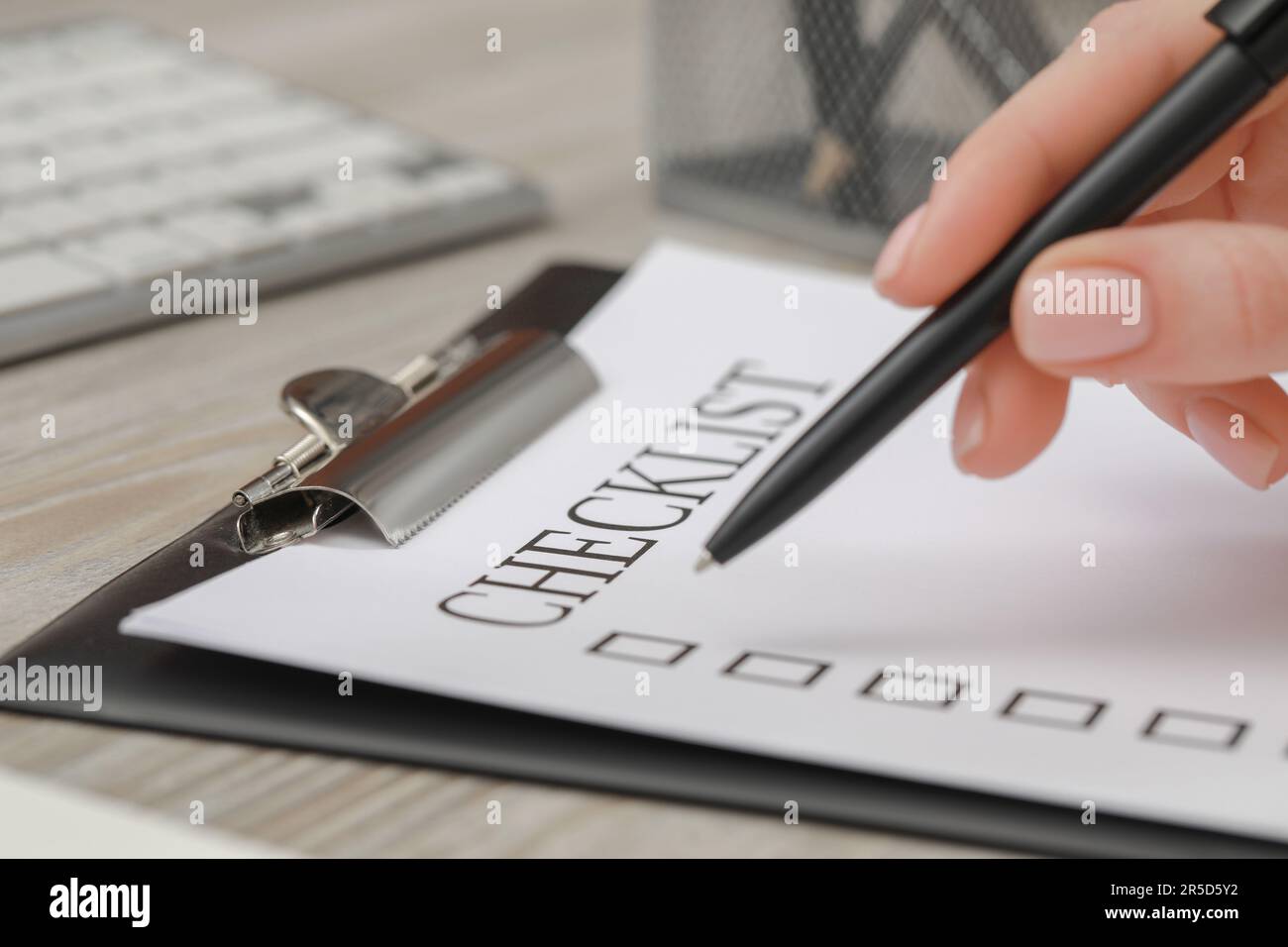 Woman filling Checklist at wooden table, closeup Stock Photo - Alamy