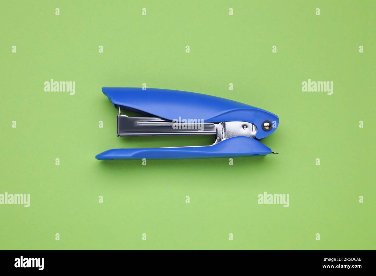 New bright stapler on green background, top view. School stationery ...