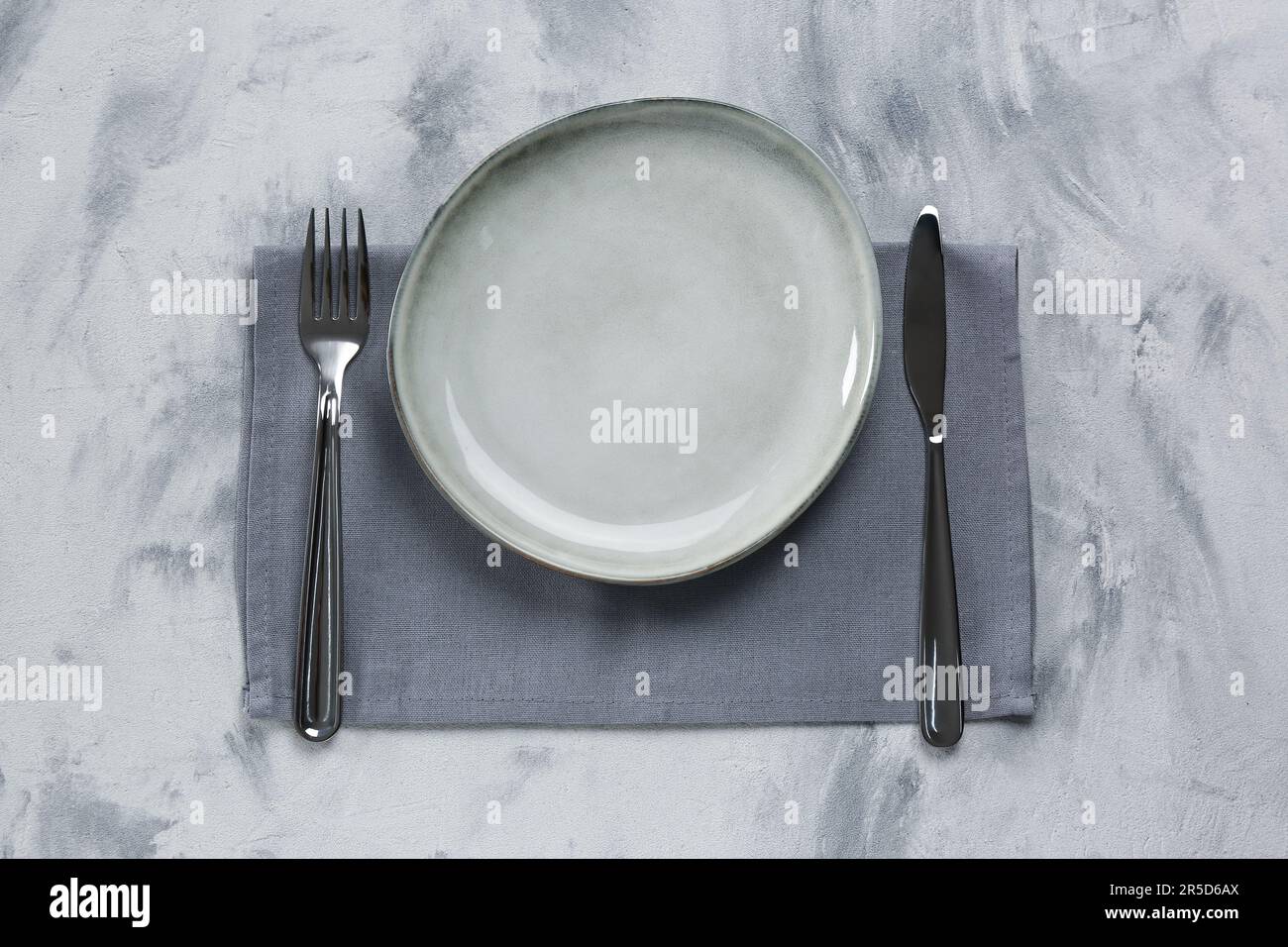 Empty plate, fork and knife on light grey table, top view Stock Photo - Alamy
