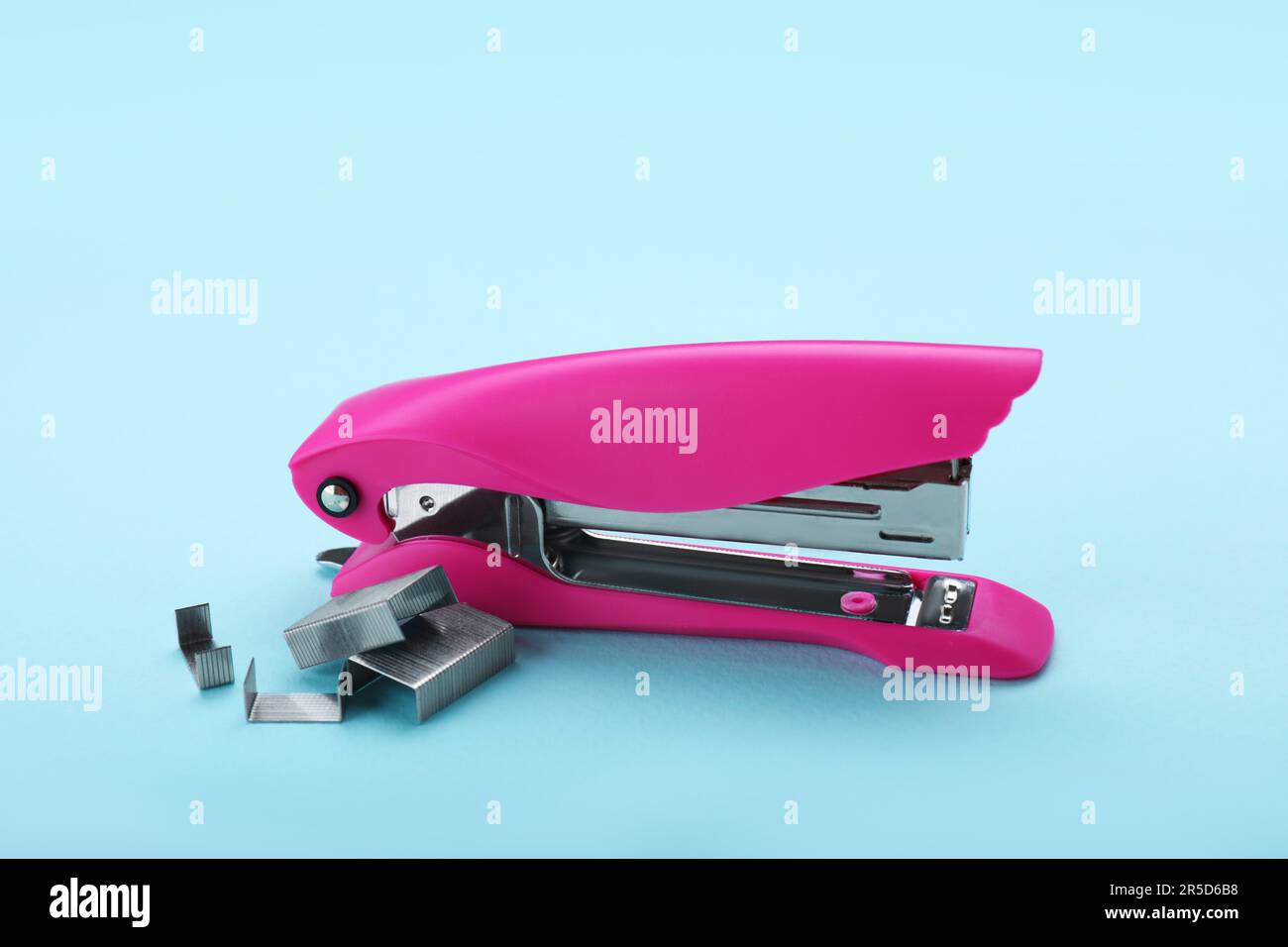 New bright stapler with staples on light blue background. School ...