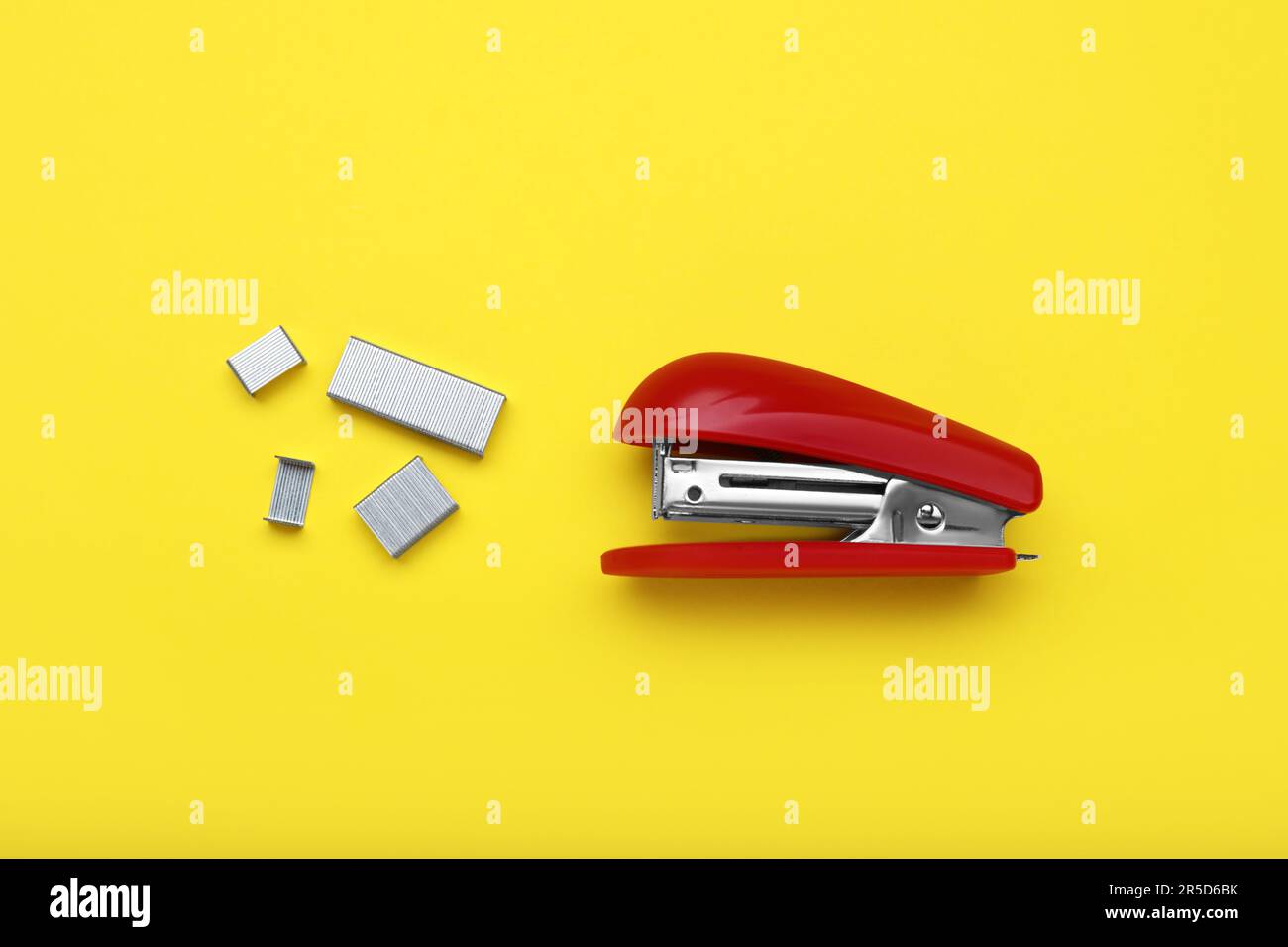 New bright stapler with staples on yellow background, fat lay. School ...