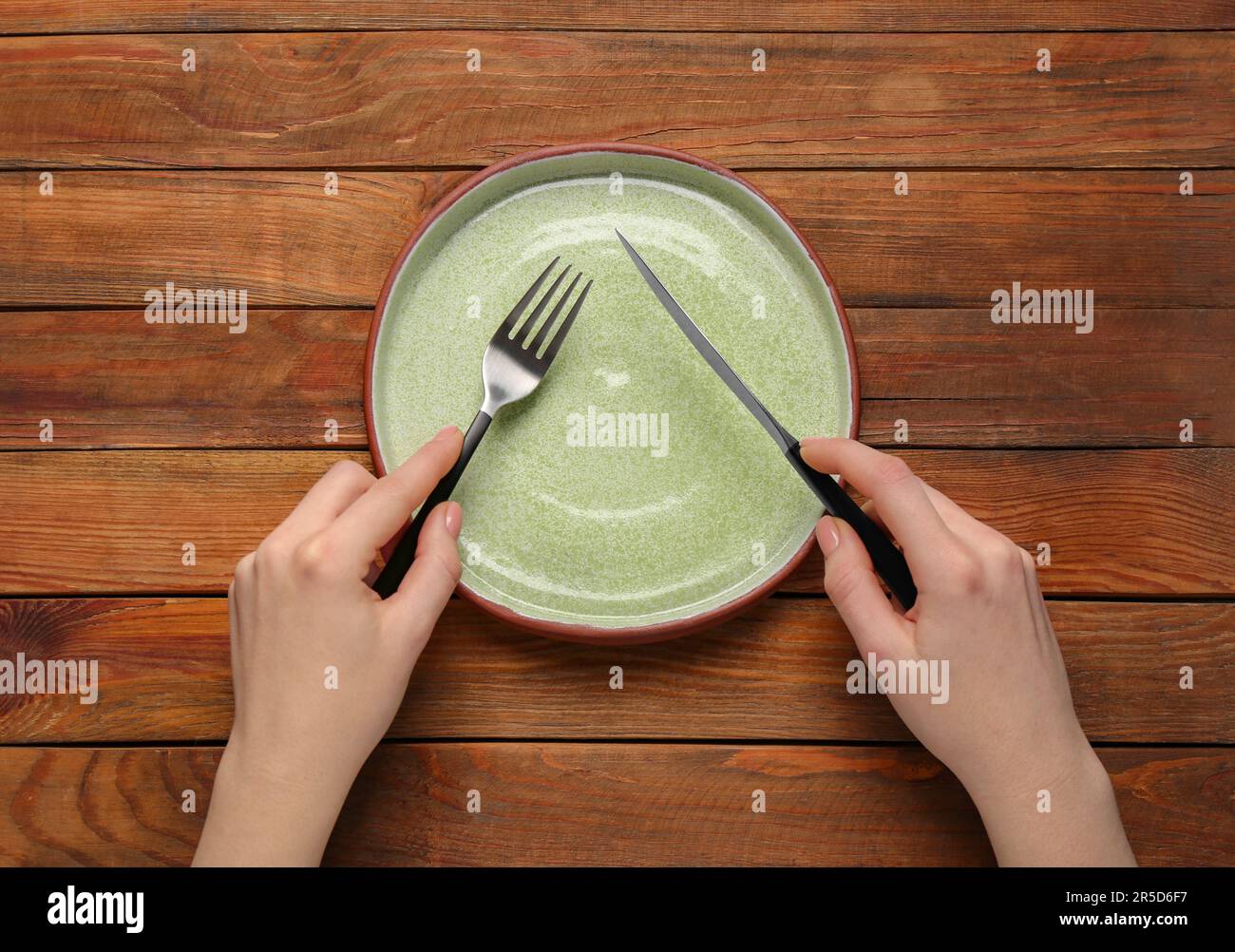 Woman with empty plate and cutlery at wooden table, top view Stock ...