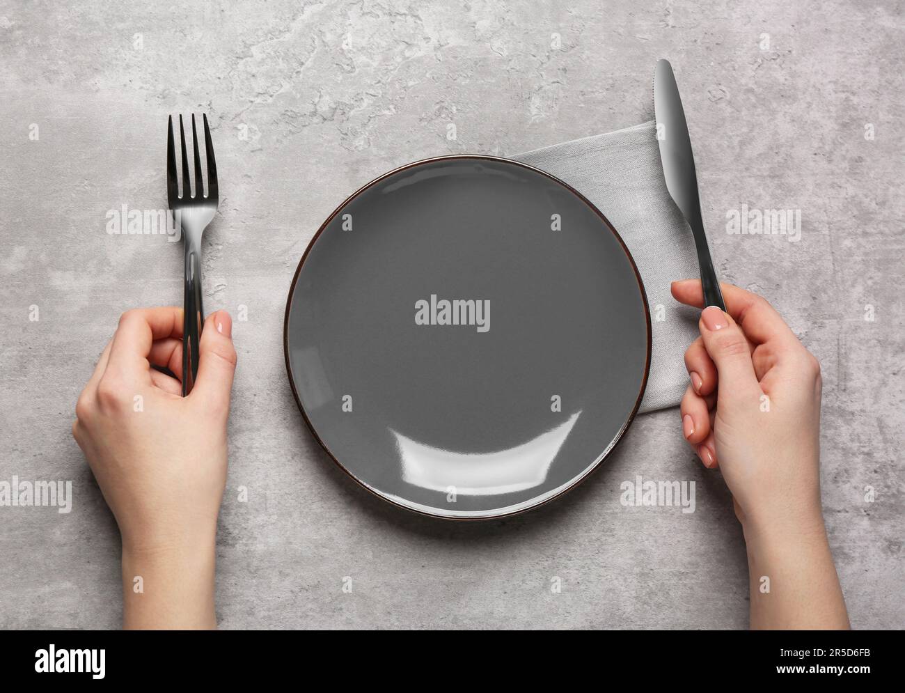 Woman with empty plate and cutlery at light grey table, top view Stock ...