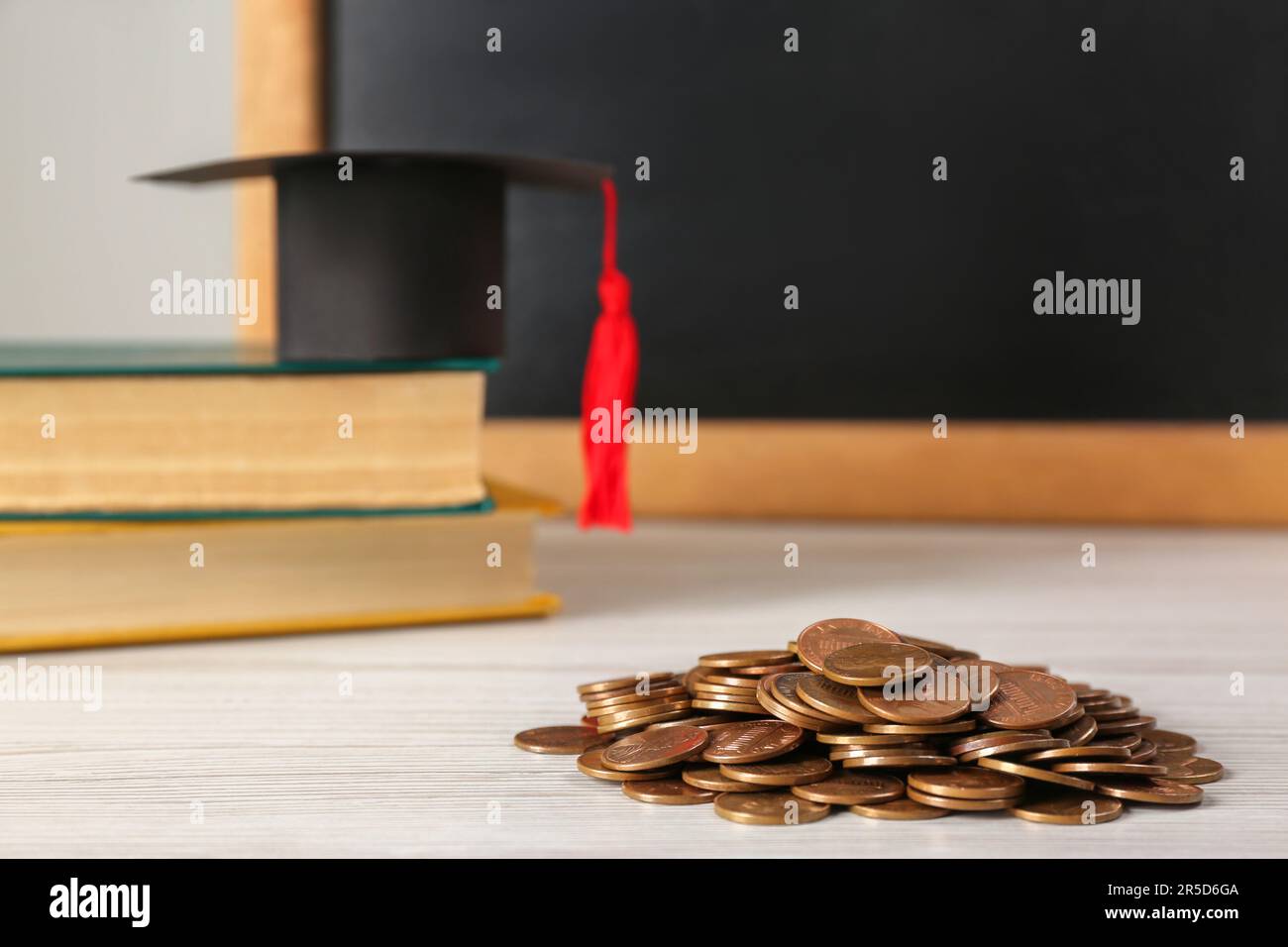 Scholarship concept. Graduation cap, books and coins on white wooden ...