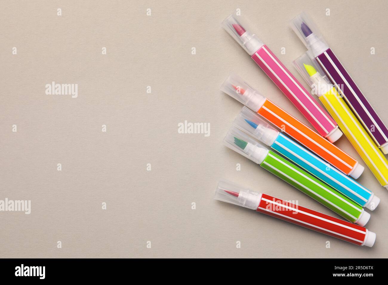 Many bright markers on light grey background, flat lay. Space for text ...