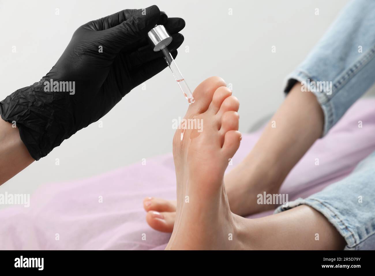 Professional master pouring oil on client's foot in beauty salon ...