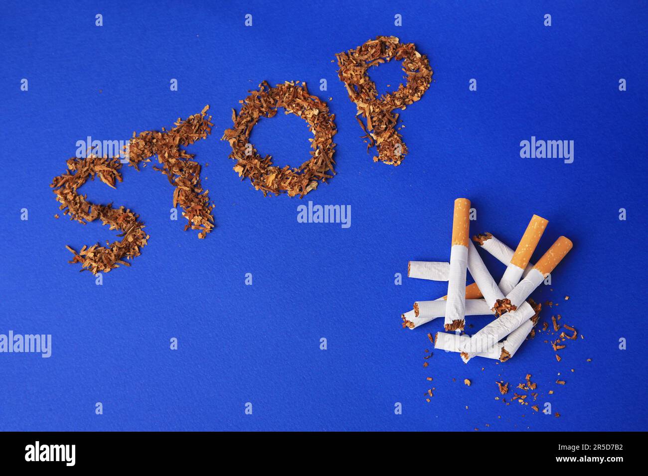 Word Stop made of dry tobacco and broken cigarettes on blue background ...