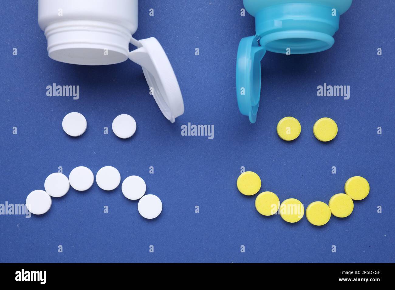 Happy, sad faces made of antidepressant pills and bottles on dark blue ...