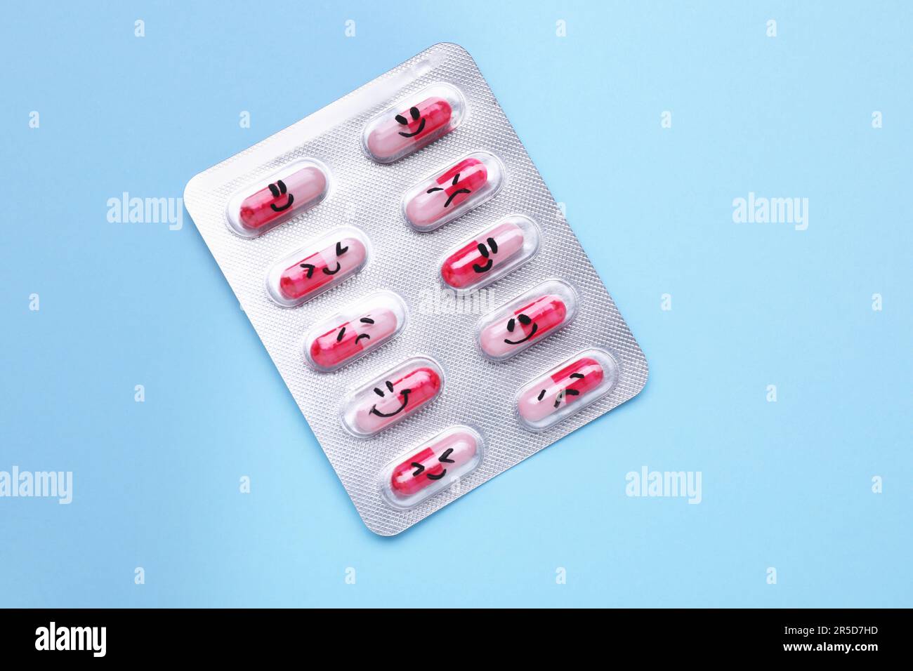 Blister of antidepressant pills with emotional faces on light blue ...