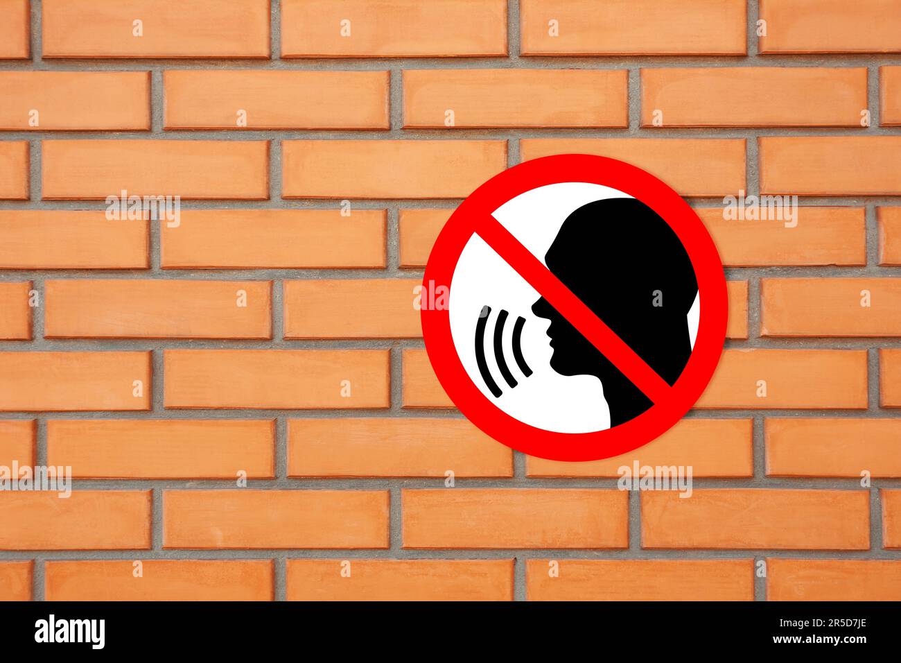 Quiet Please prohibition sign with human head image on orange brick ...