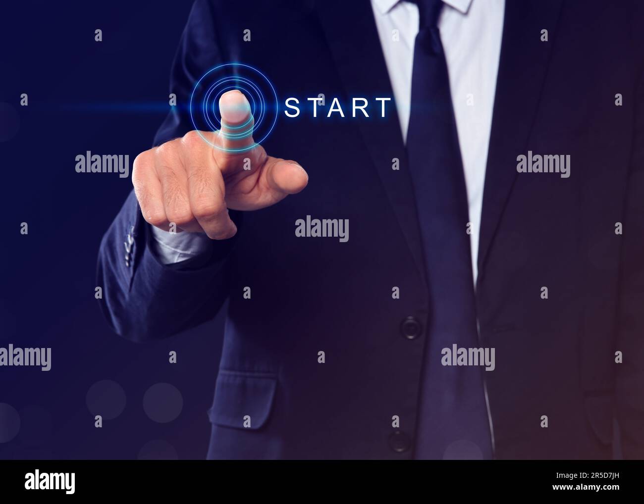 Man pressing start button on virtual screen against dark blue ...