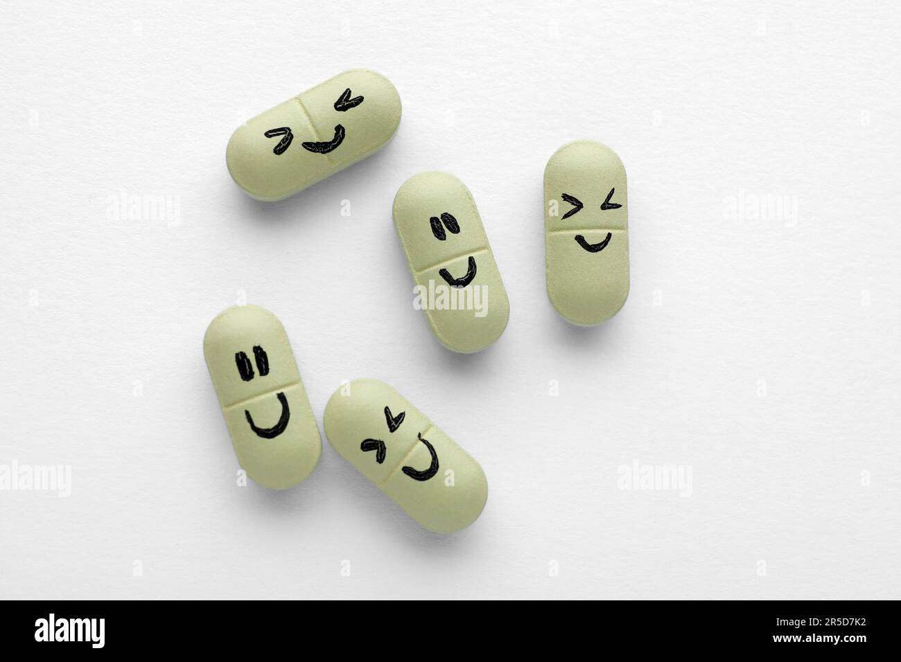 Antidepressant pills with emotional faces on white background, top view ...