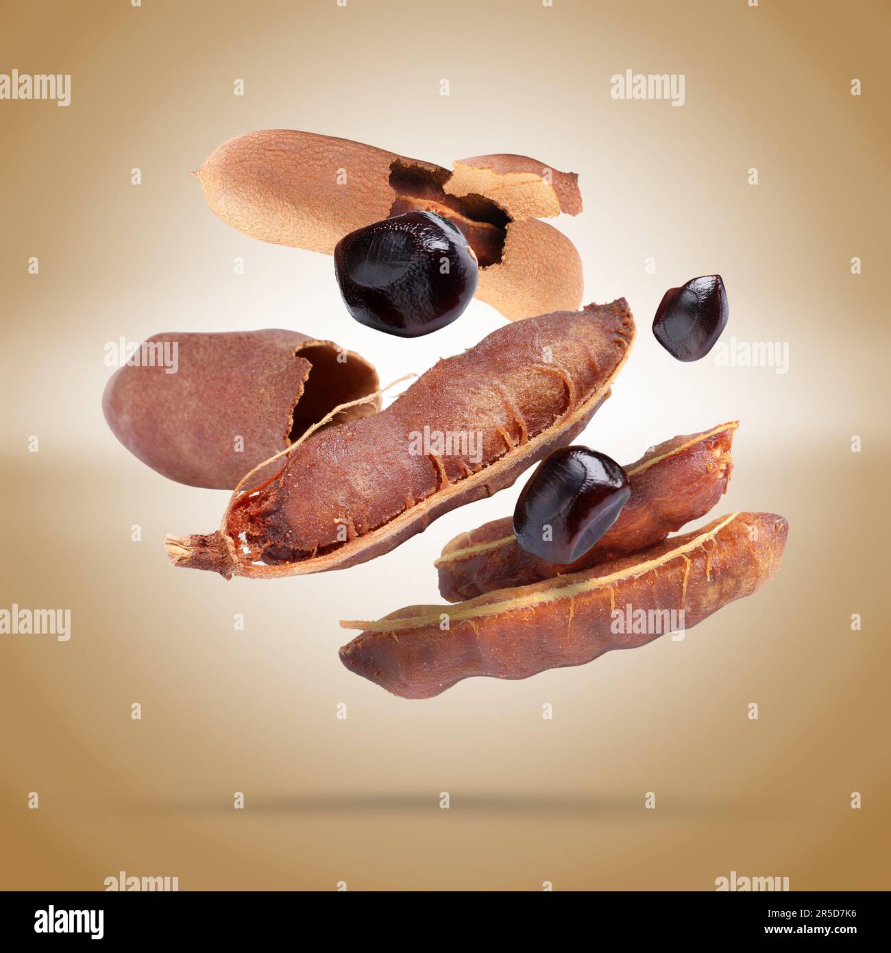 Ripe tamarind pods and seeds falling on light brown background Stock ...