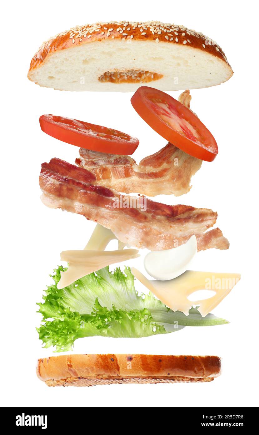 Tasty cut bagel with different ingredients flying on white background ...