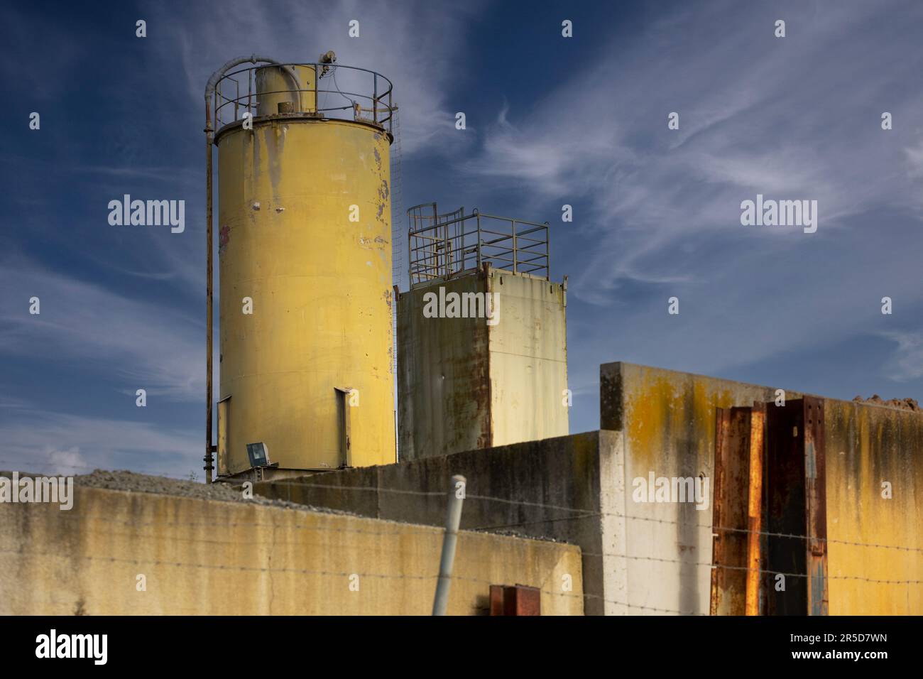 Cement Silo's and a concrete wall with rusty girder against a blue sky ...