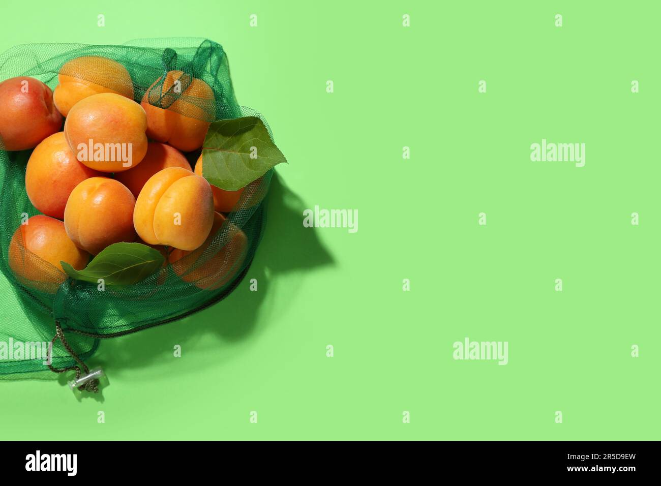 Eco bag with fresh apricots and leaves on green background Stock Photo ...