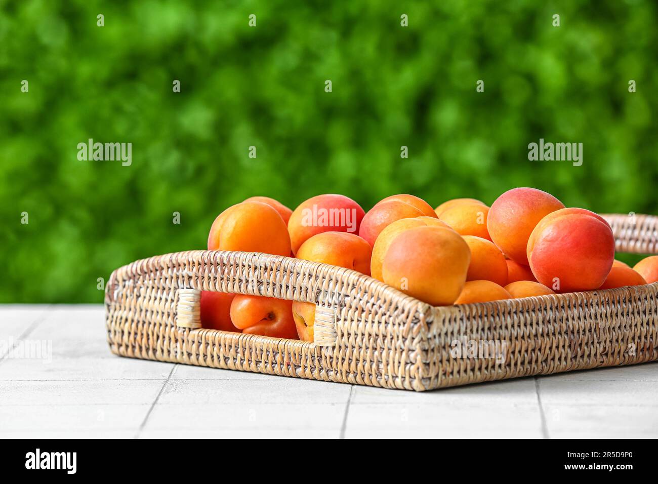 Wicker tray with fresh apricots on white tile table outdoors Stock ...