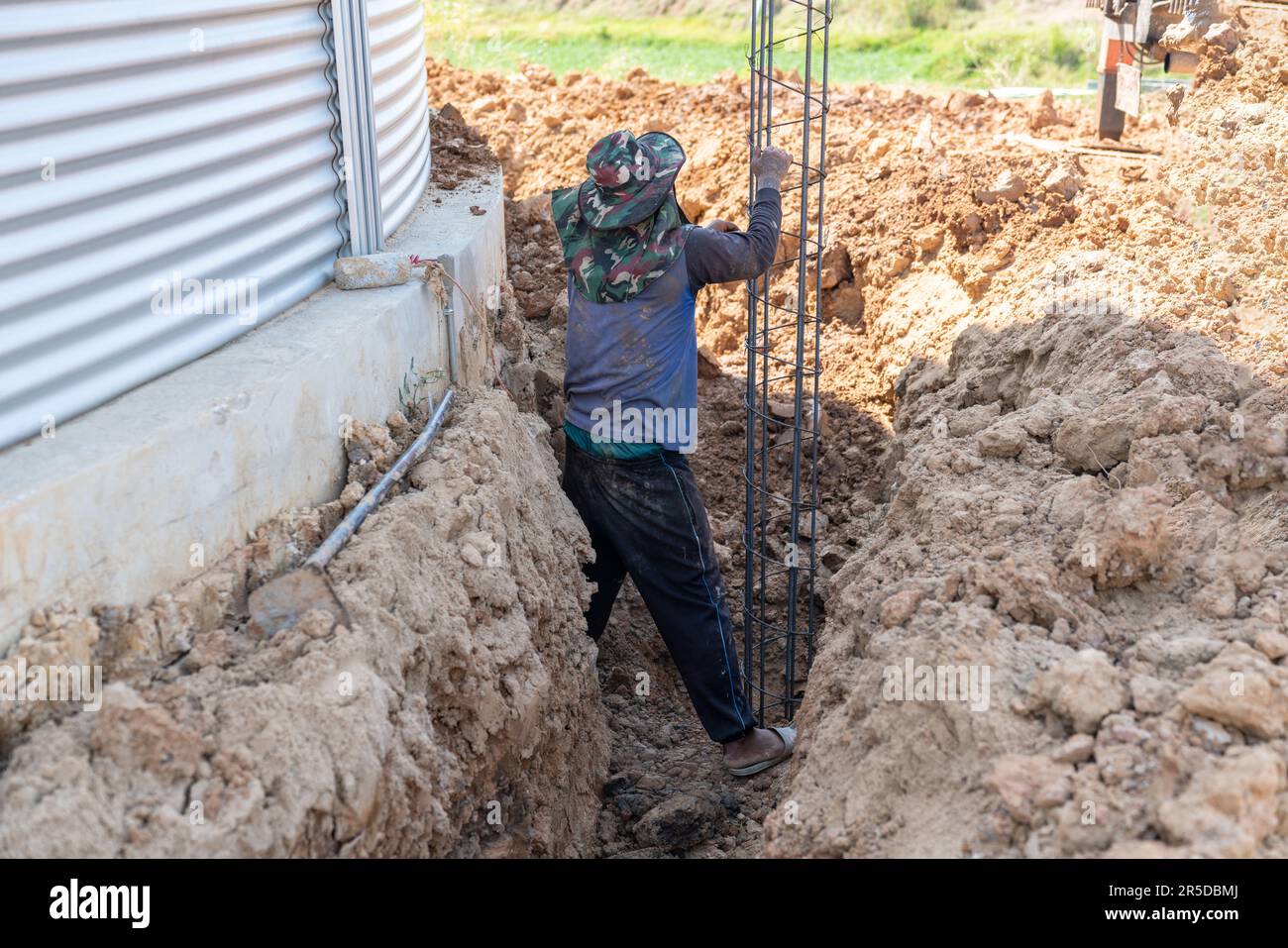 Worker drop steel bar structure to pit of pile in construction site ...