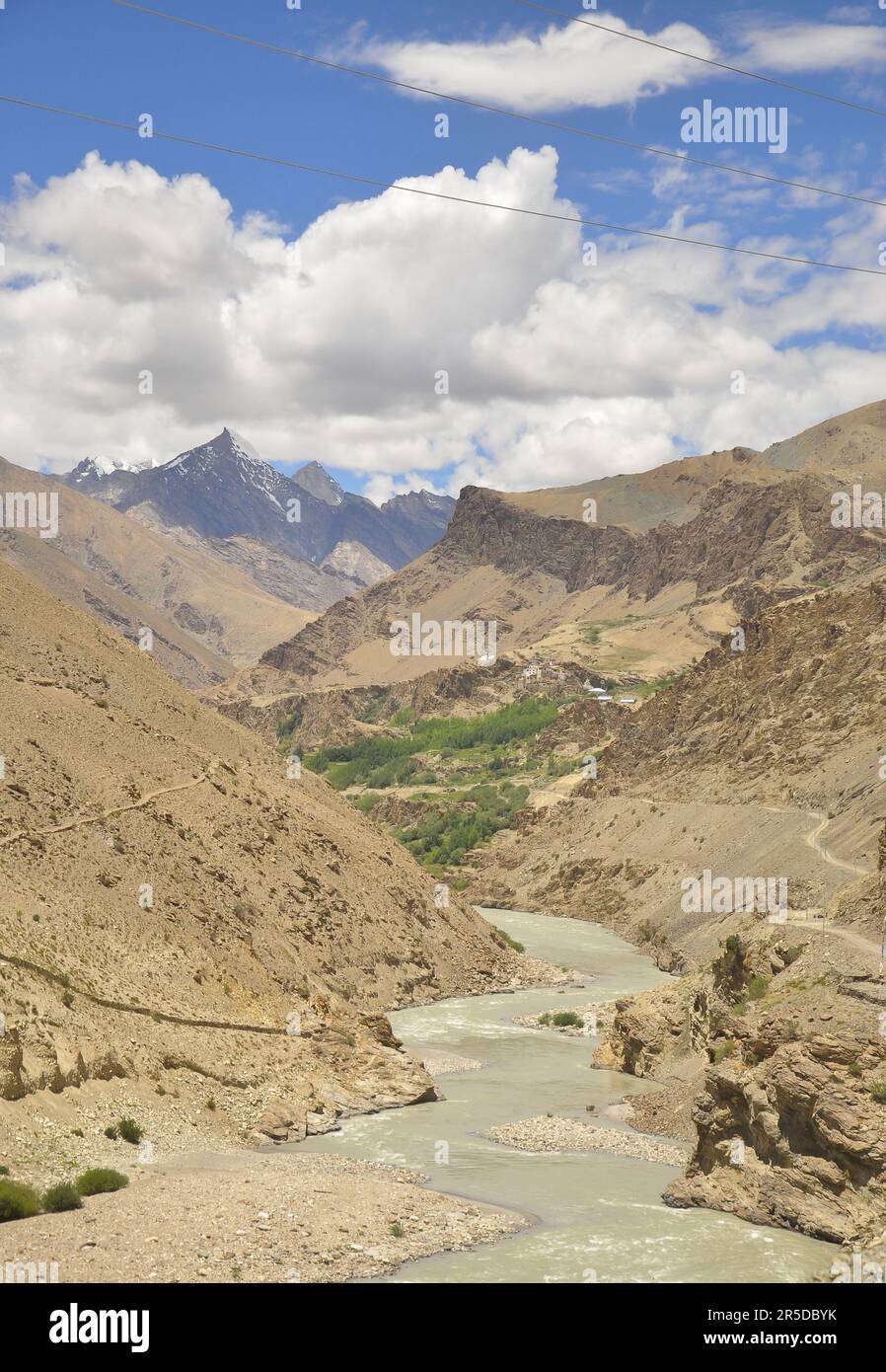 Scenic view of flowing river in between rocky mountains with clouds in ...