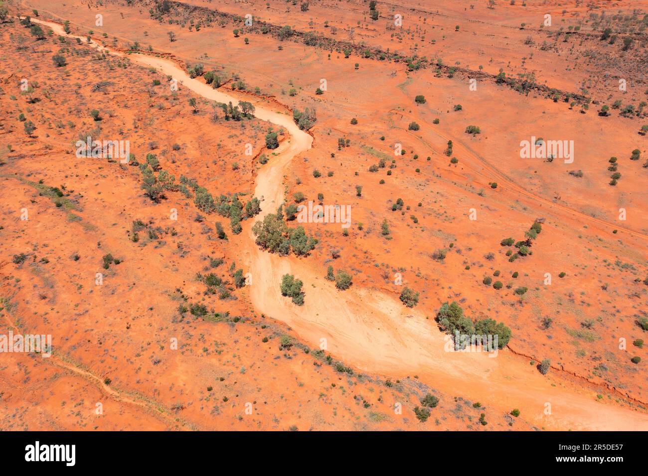 Aerial view of a dry sandy river bed winding through a barren outback ...