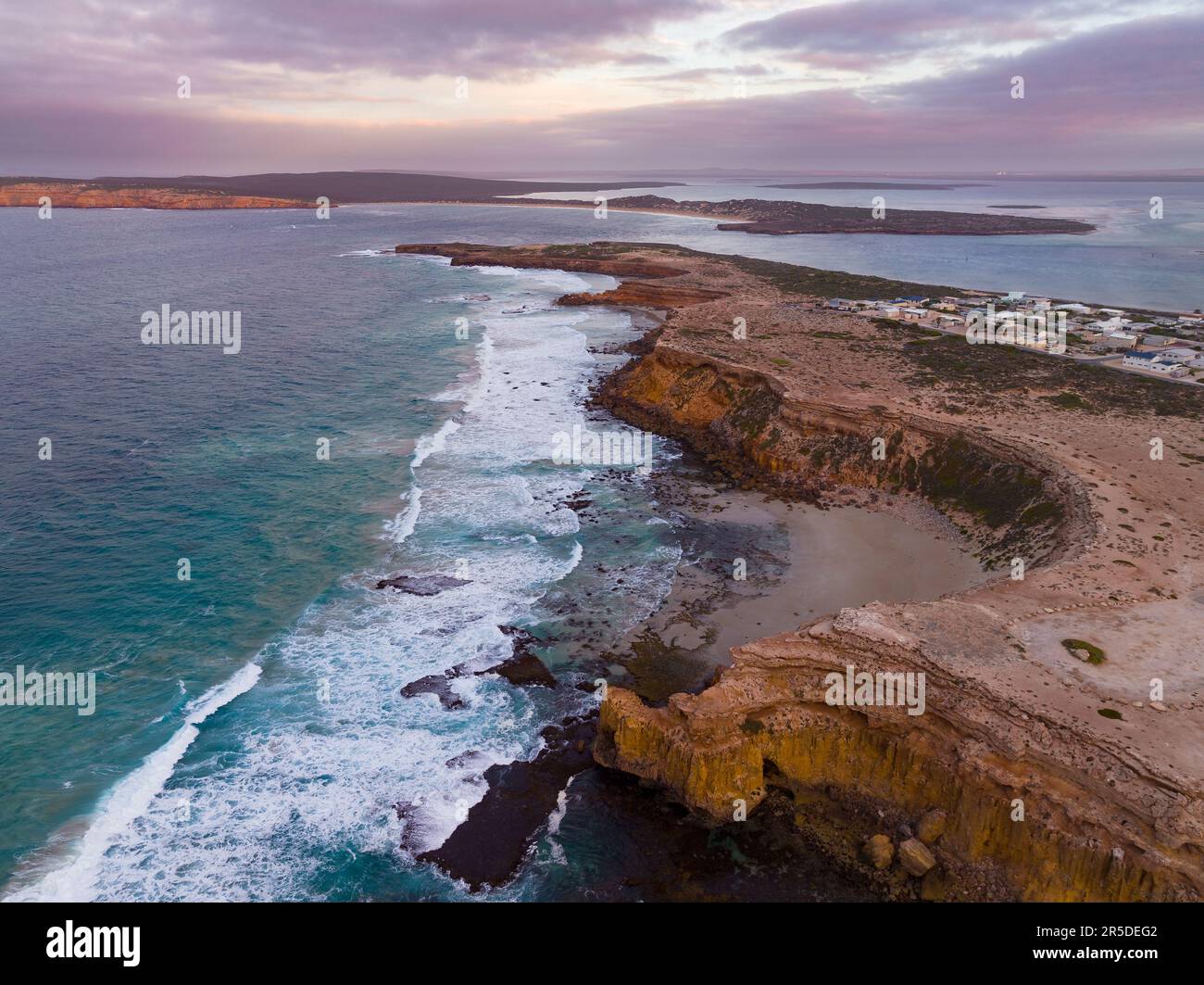 Aerial view of waves breaking on a rugged coastline just before dawn at ...