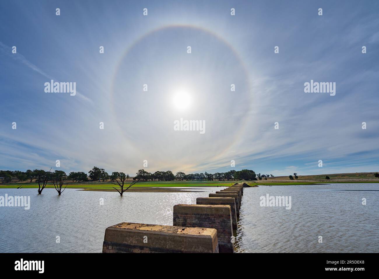 Low angled view of a Solar Halo over ruins of viaduct pillars in a lake ...