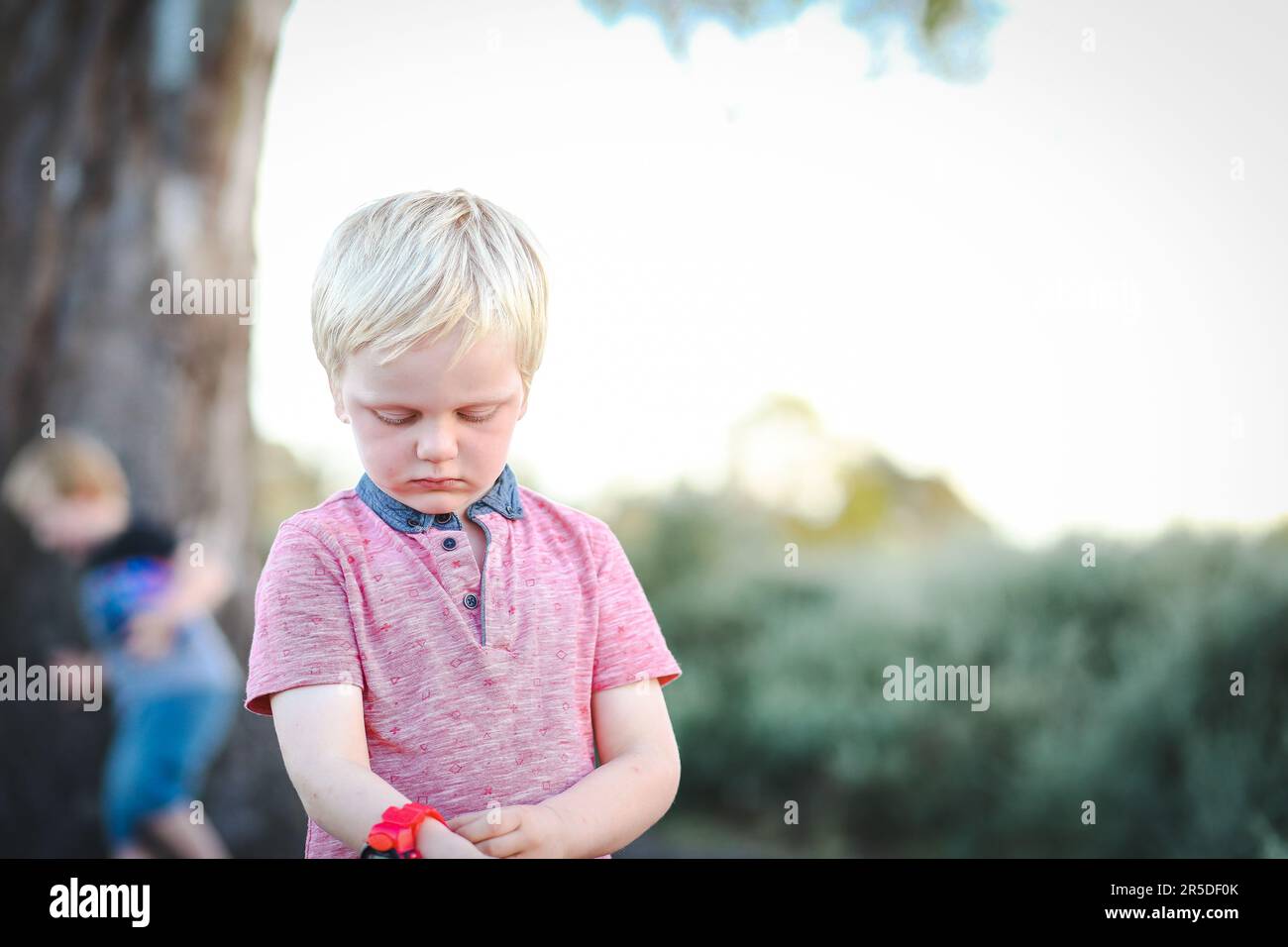Little boy wearing bright red watch at the park with other children ...